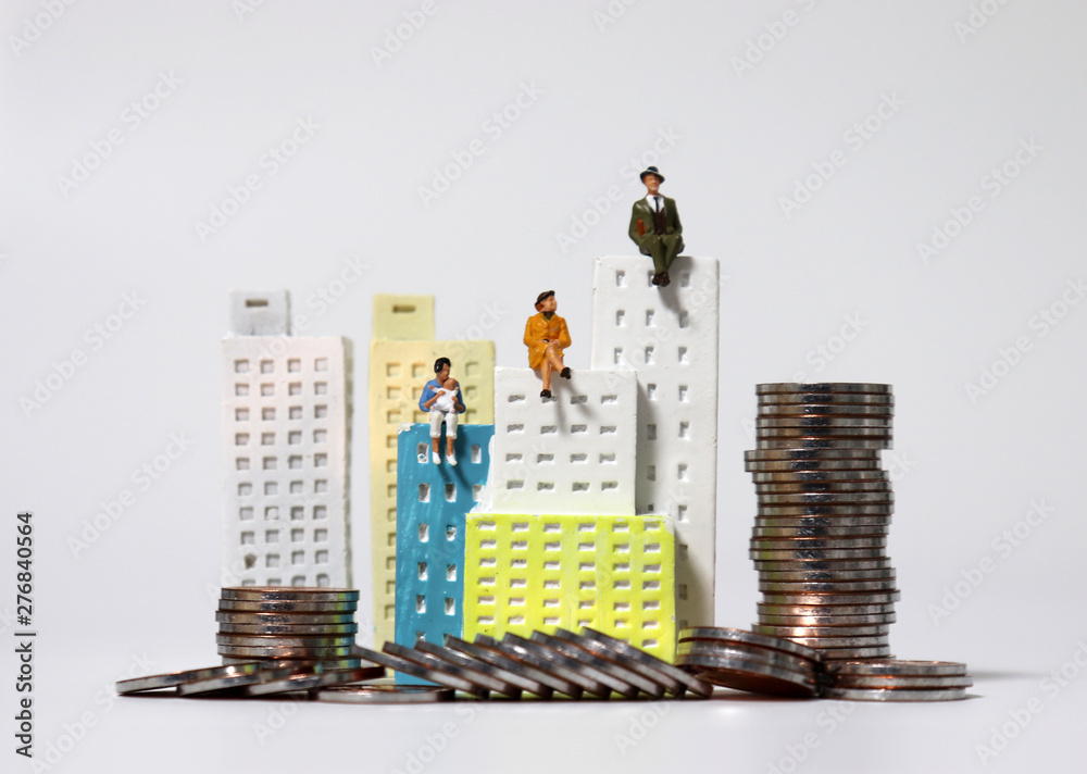 Miniature people sitting on top of a miniature building and pile of ...