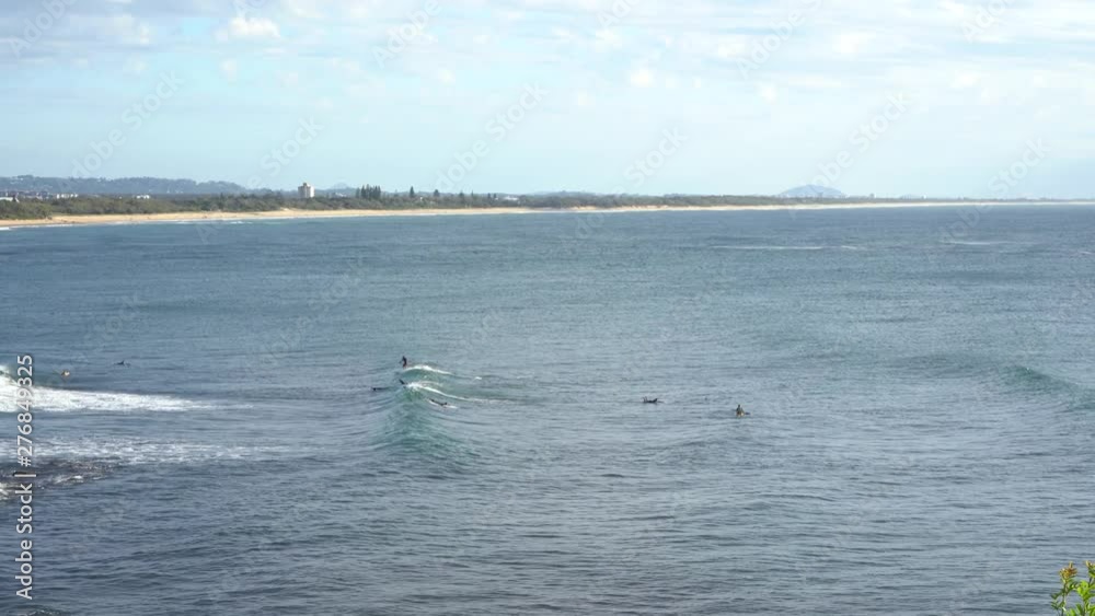 Very wide shot of people surfing blue and white waves in large ocean ...