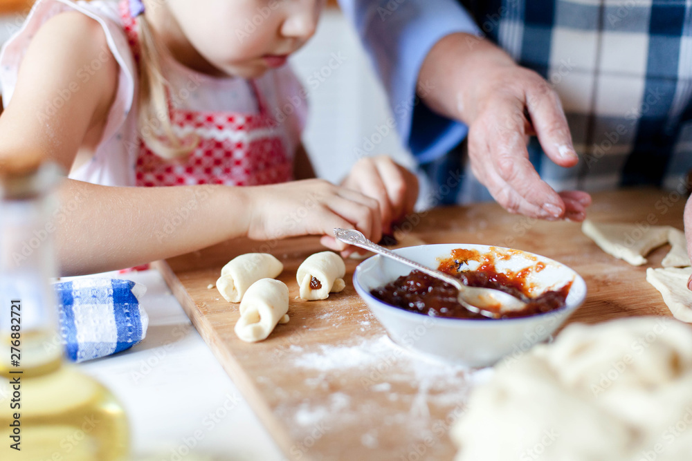 Kid makes croissants with jam. Family is cooking together at home ...