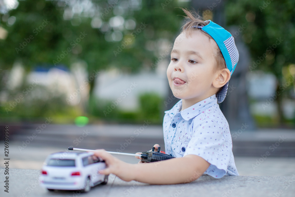 The boy is controling the toy car with a remote control. child's face ...