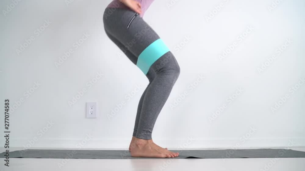 Resistance band fitness woman doing squat exercise with fabric booty ...