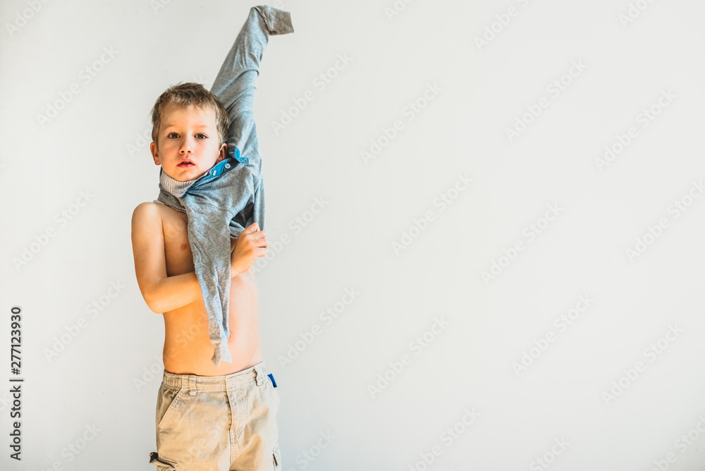 Child trying to take off his shirt and undress on his own. Stock Photo ...