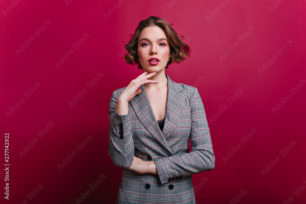 Interested businesswoman with trendy makeup posing on claret background ...