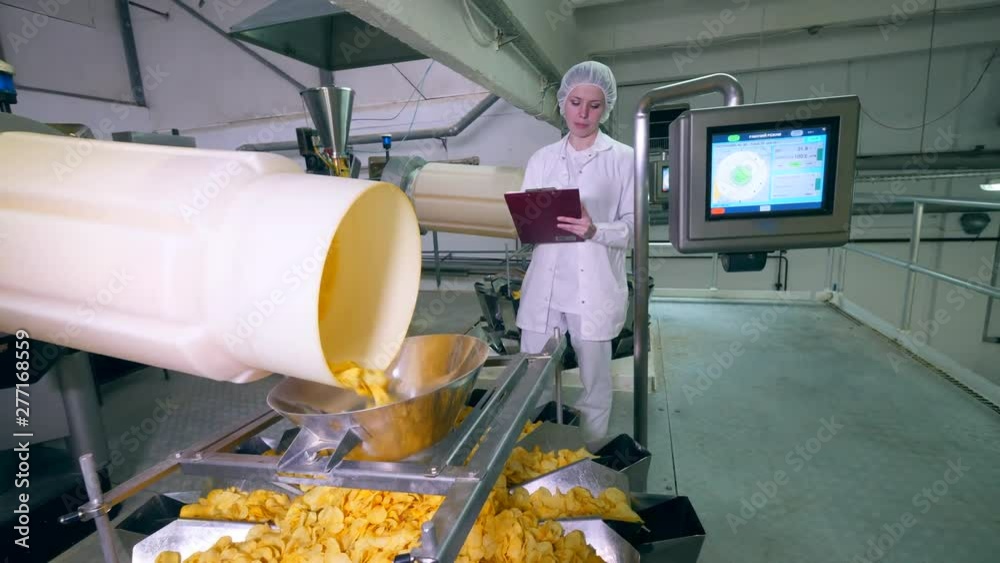 One woman checks work of automated conveyor, moving chips into a ...