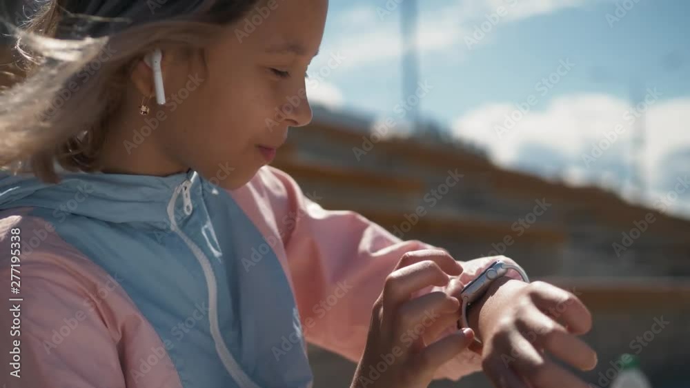 Kid Using Smartwatch or Smart Watch in park sitting on grass, Child in ...