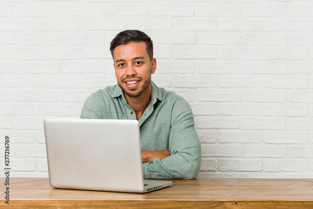 Foto de Young filipino man sitting working with his laptop who feels ...