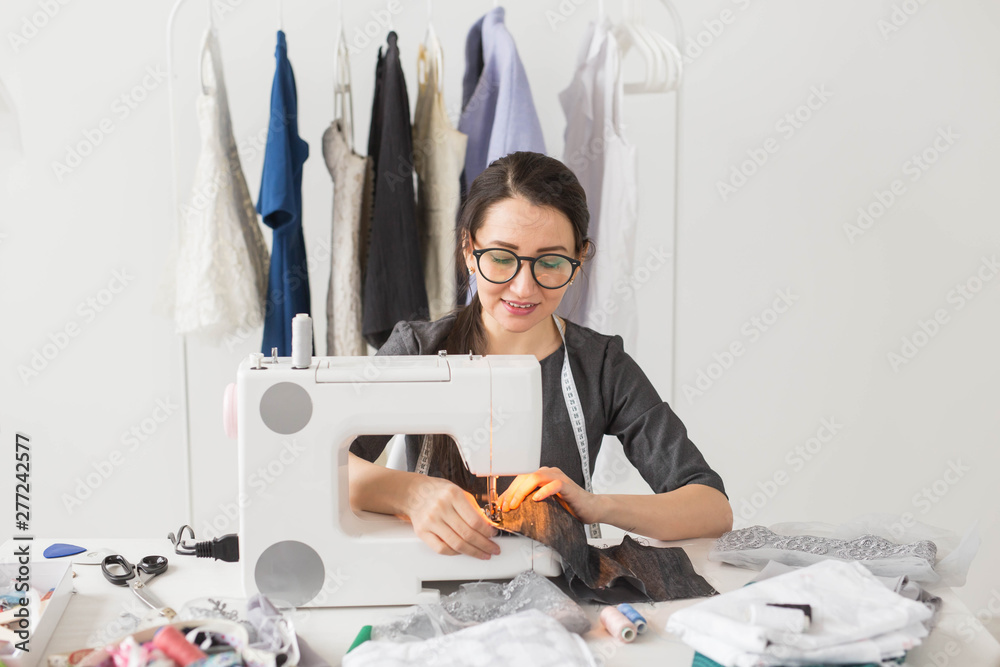people, fashion and showroom concept - young fashion designer sews ...