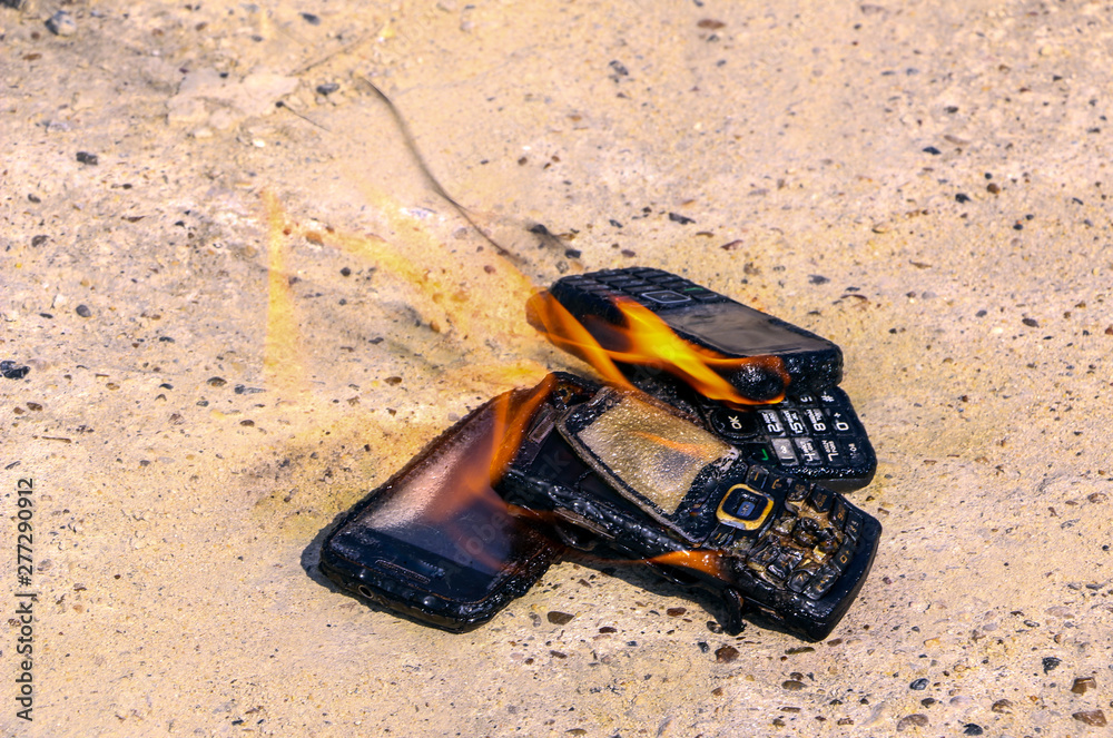 burnt mobile phones on textural concrete background. Concept: Danger of ...