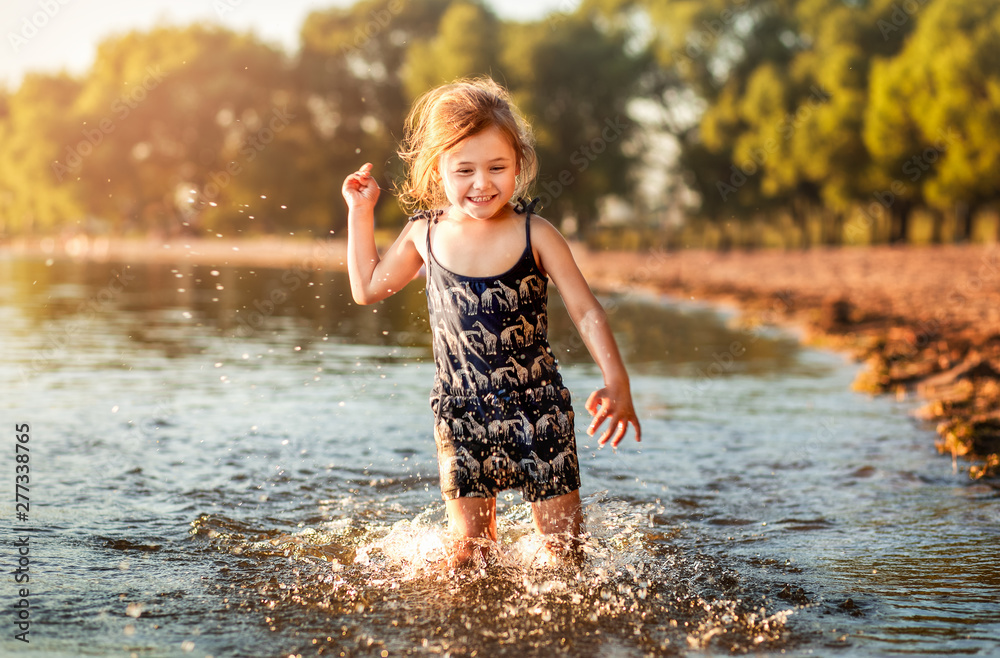 little girl by the river in summer splashes water Stock Photo | Adobe Stock