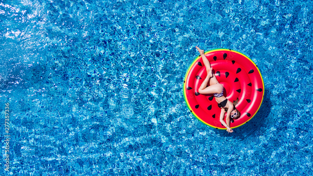 Top view of young woman relaxing on watermelon in pool. Young girl ...