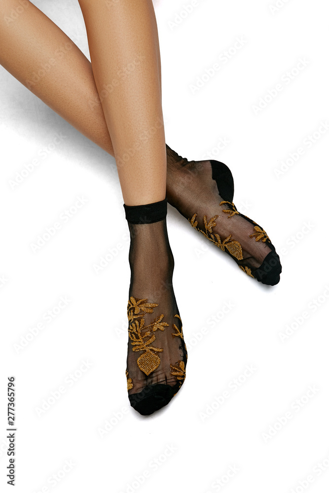 Cropped view of lady's legs in black nylon socks, adorned with ...