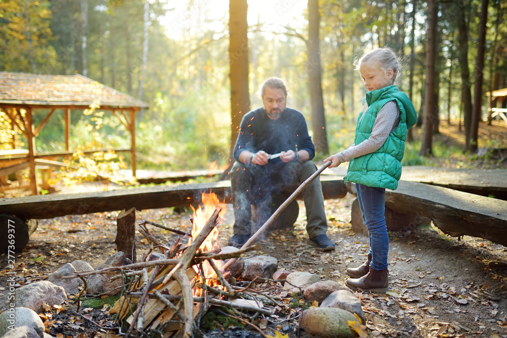 Cute young girl learning to start a bonfire. Father teaching her ...