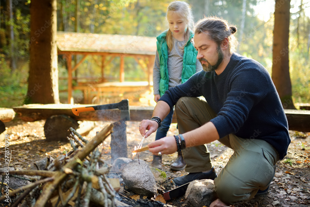 Cute young girl learning to start a bonfire. Father teaching her ...