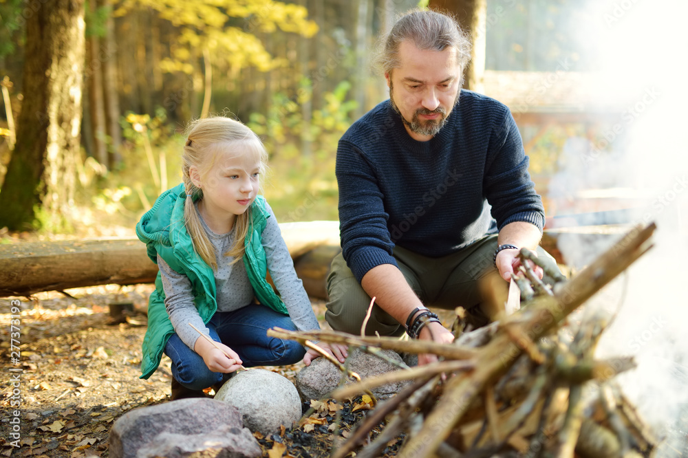 Cute young girl learning to start a bonfire. Father teaching her ...