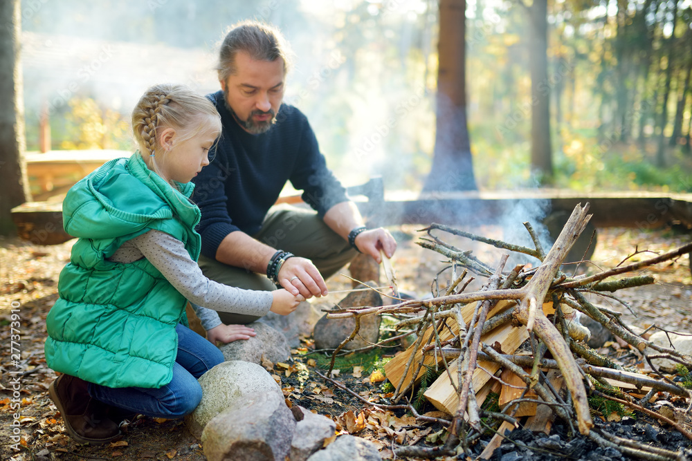 Cute young girl learning to start a bonfire. Father teaching her ...