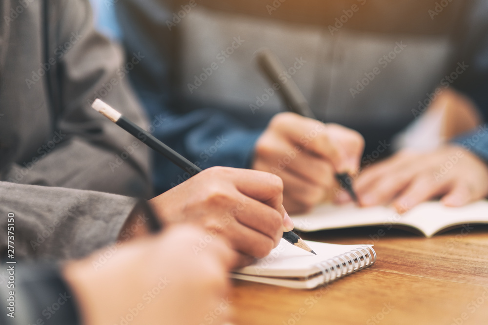 Foto de Closeup image of many people writing on blank notebook together ...
