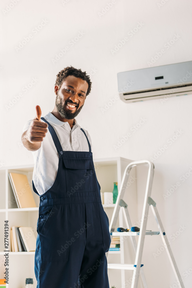 happy african american repairman standing on ladder under air ...