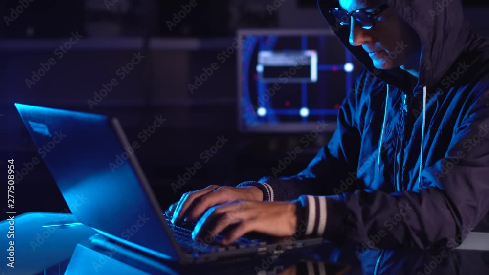 Hacker typing program code while committing a cybercrime hacking a ...