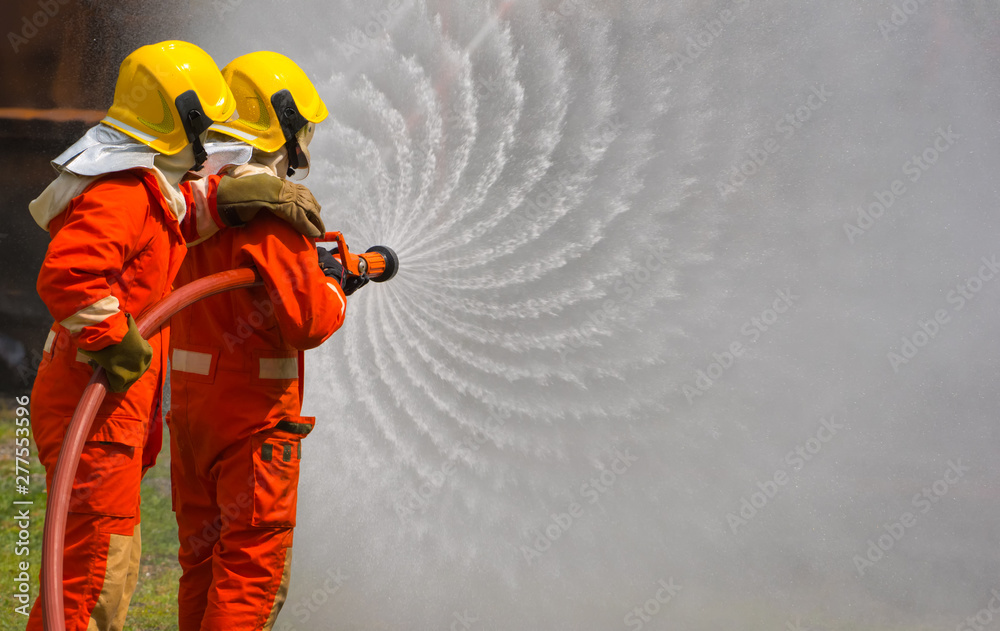 Two brave firefighter using extinguisher and water from hose for fire ...