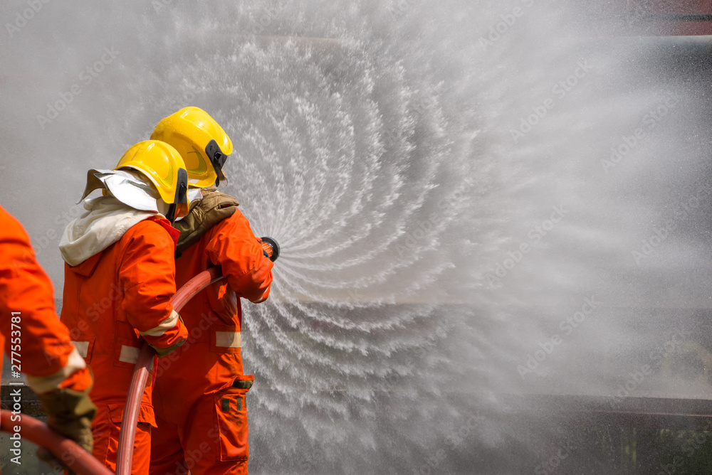 Two brave firefighter using extinguisher and water from hose for fire ...