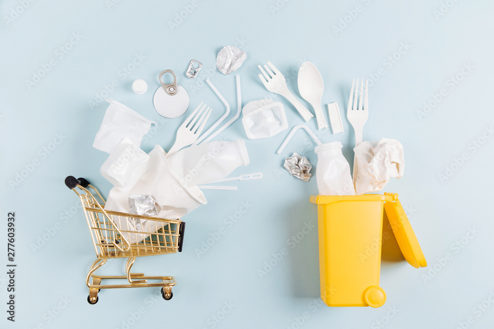 White single use plastic falling out of shopping cart in garbage bin ...