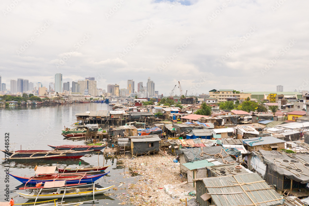 Manila slums on the background of a big city. Houses and boats of the ...
