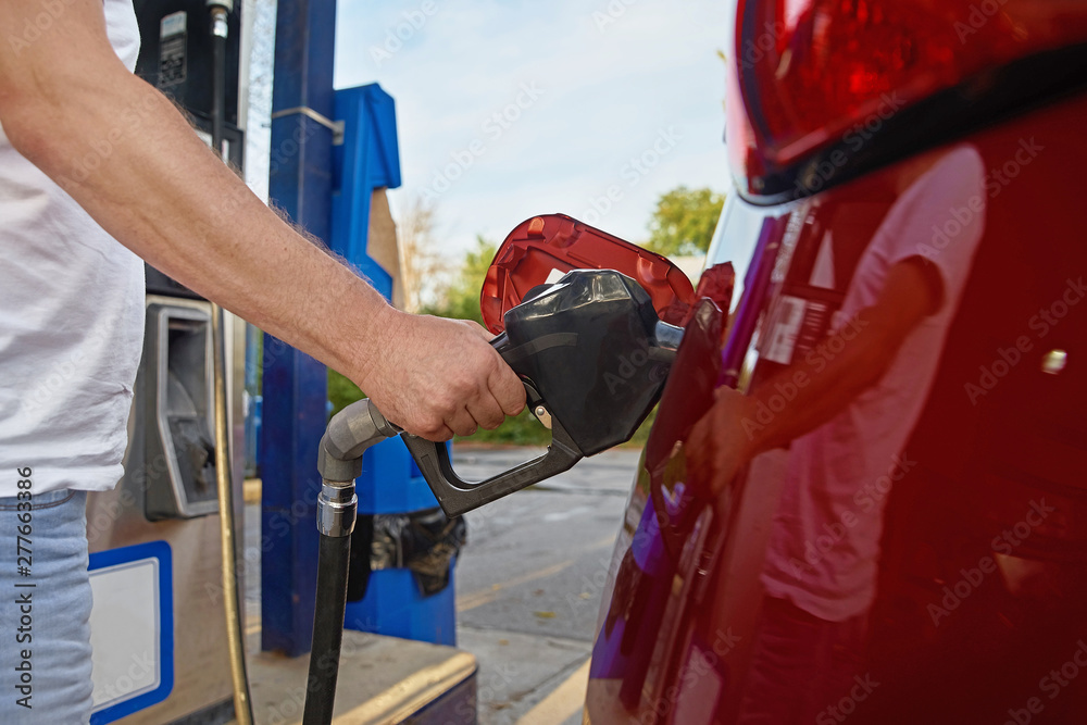 Man refuses his red car with gasoline at a gas station. Hand and black ...