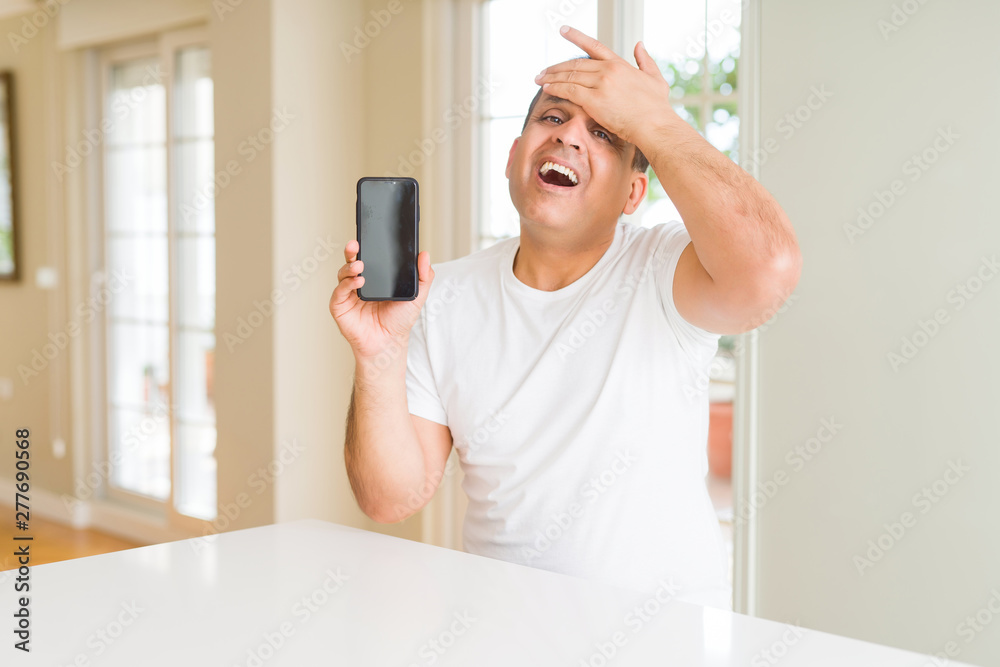 Middle age man showing smartphone screen stressed with hand on head ...