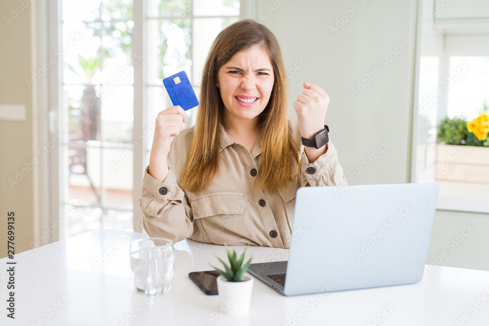 Beautiful young woman shopping online using laptop and credit card ...