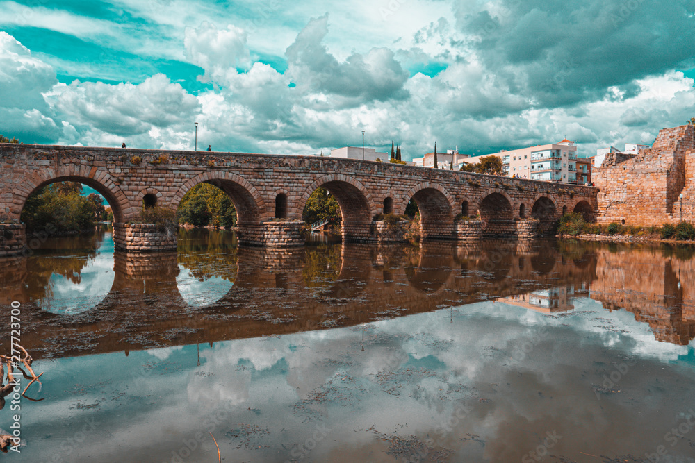 Orange and teal view of the Roman bridge of Merida with its reflection ...