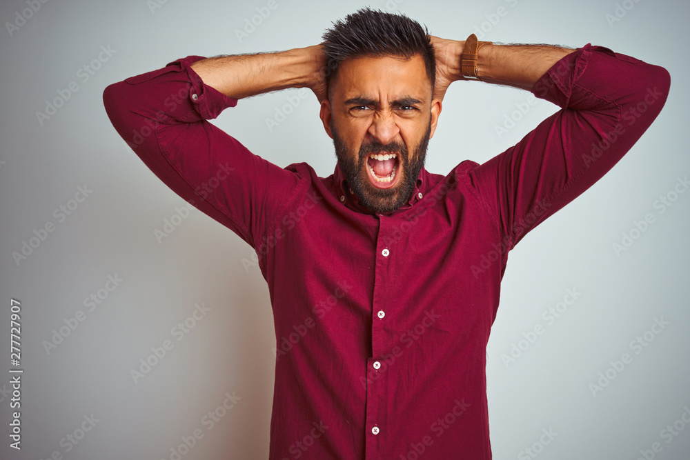 Young indian man wearing red elegant shirt standing over isolated grey ...