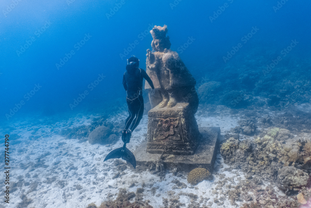A free diver pays tribute to an underwater religious structure using a ...