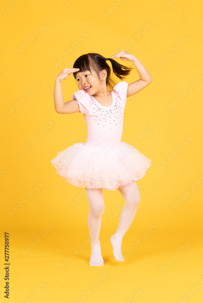 Cute ballerina little Asian girl in pink dancer over a yellow ...