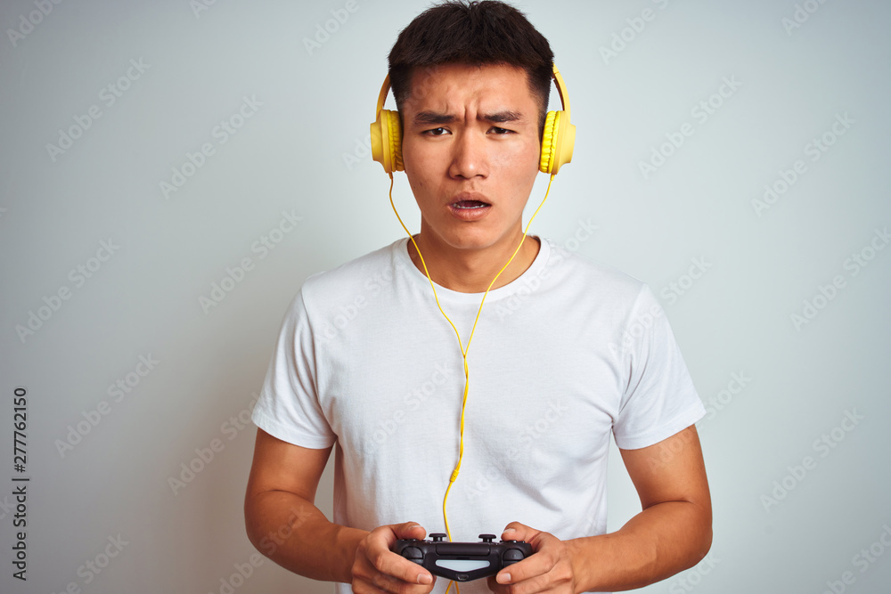 Young asian chinese gamer man playing video game standing over isolated ...