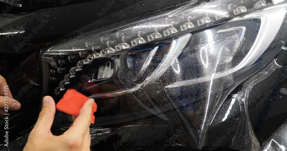Close up to PPF installation process on a front headlight and hood. PPF ...