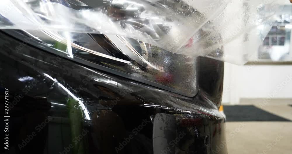 Close up to PPF installation process on a front headlight and hood. PPF ...