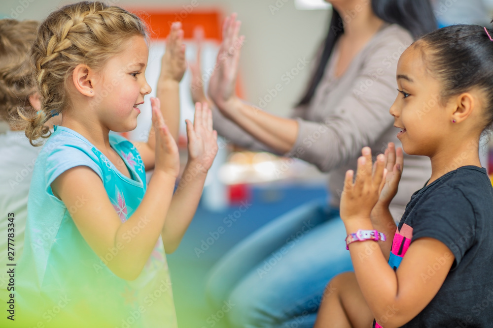 Happy children and pre-school teacher clapping hands in kindergarten ...