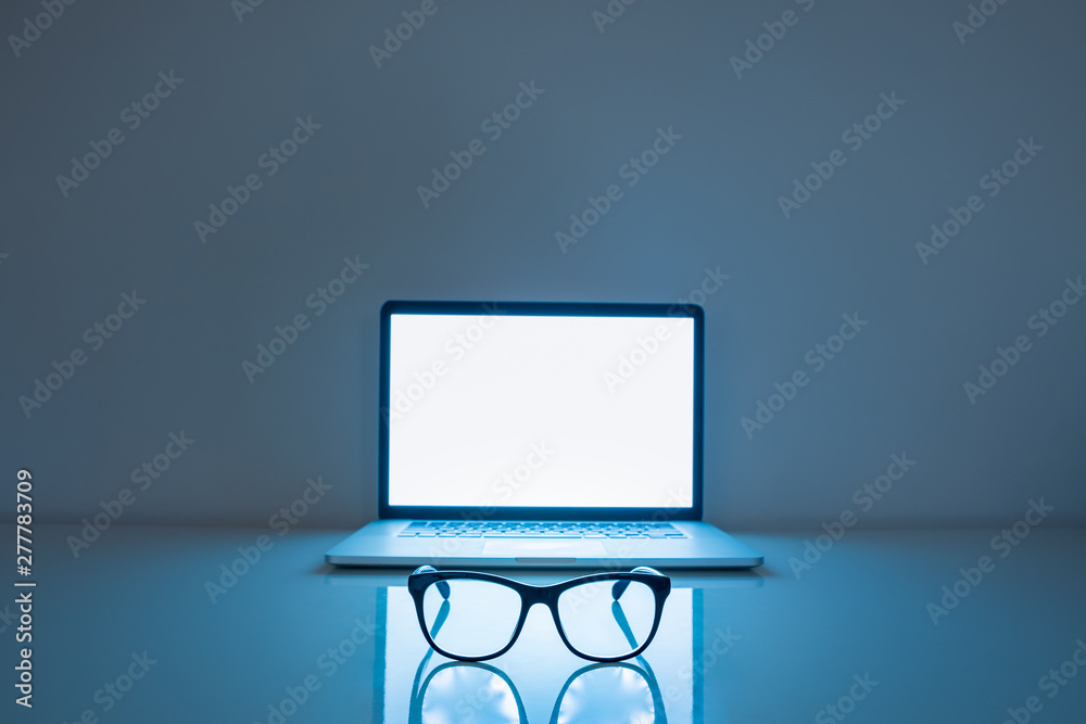 Computer eyeglasses in front of a laptop, low-key image. Blue light ...