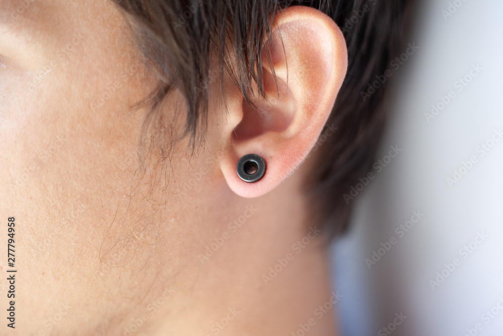 piercing in the ear, tunnels in the ears of a young man lifestyle Stock Photo | Adobe Stock