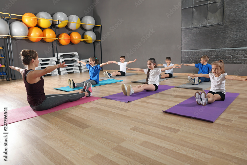 Cute little children and trainer doing physical exercise in school gym ...