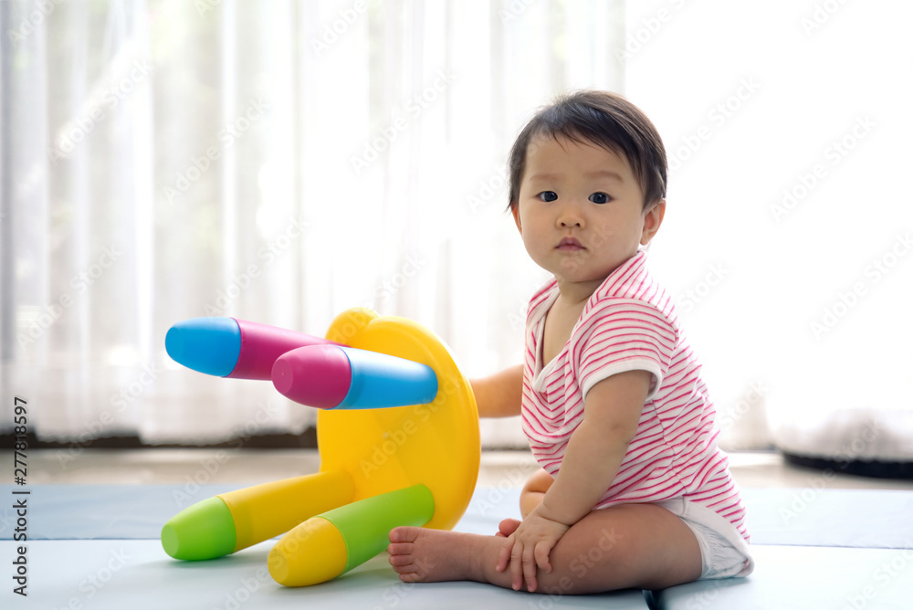 Asian cute baby sitting and playing a colorful plastic small chair on ...