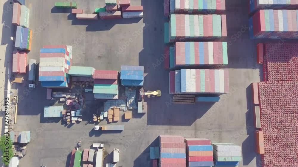 Vertical pan of a very large gated container yard with trucks, a ...