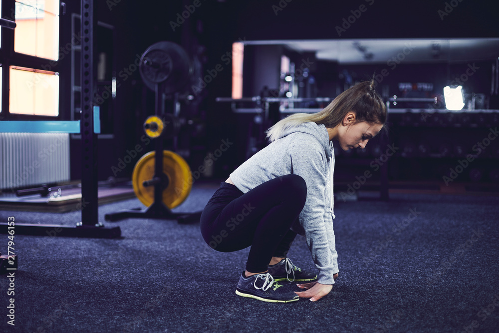 Side profile of young woman stretching on the floor at fitness centre ...