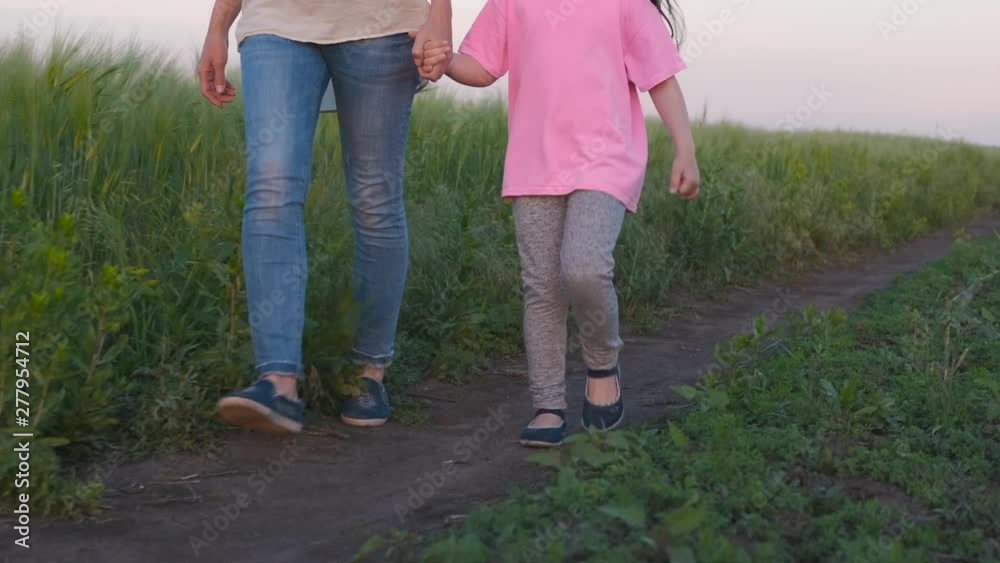 Walk with mom. A cute little girl walks holding her mother's hand in ...
