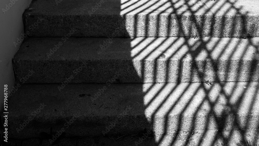 Black and white image of old stone steps with harsh shadows cast from ...