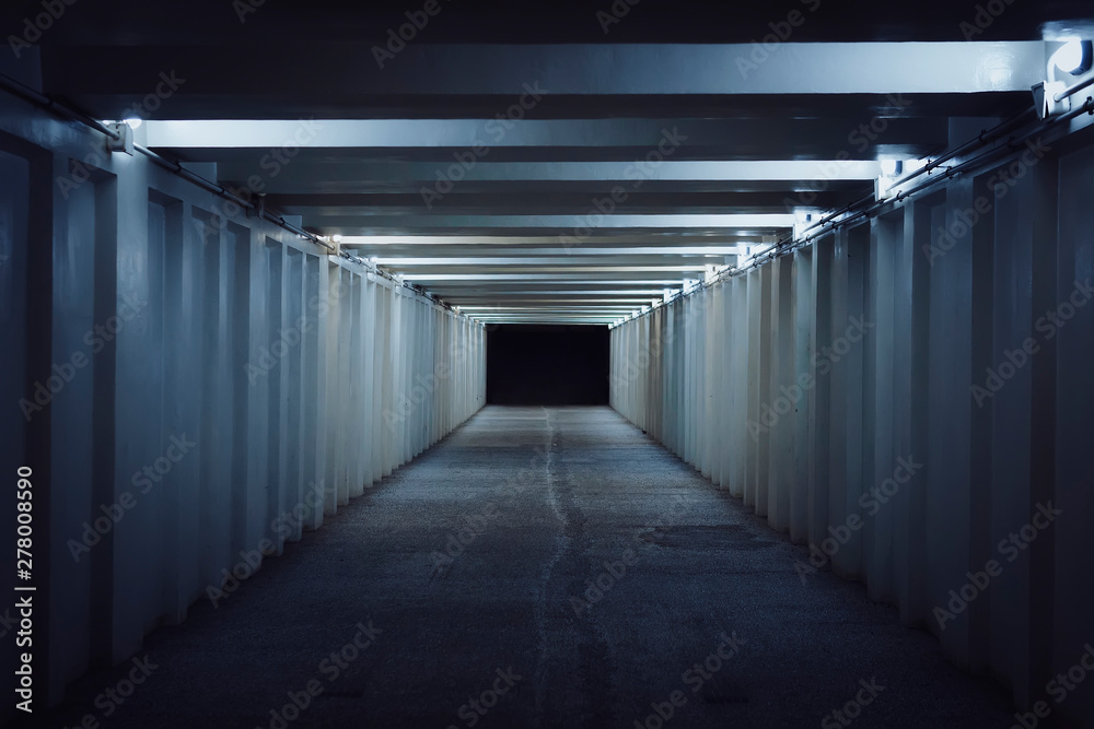Underground pedestrian crossing. A long concrete tunnel with lanterns ...