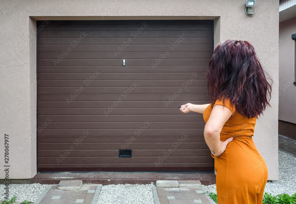 Garage door PVC. Girl or young woman holds remote controller for ...