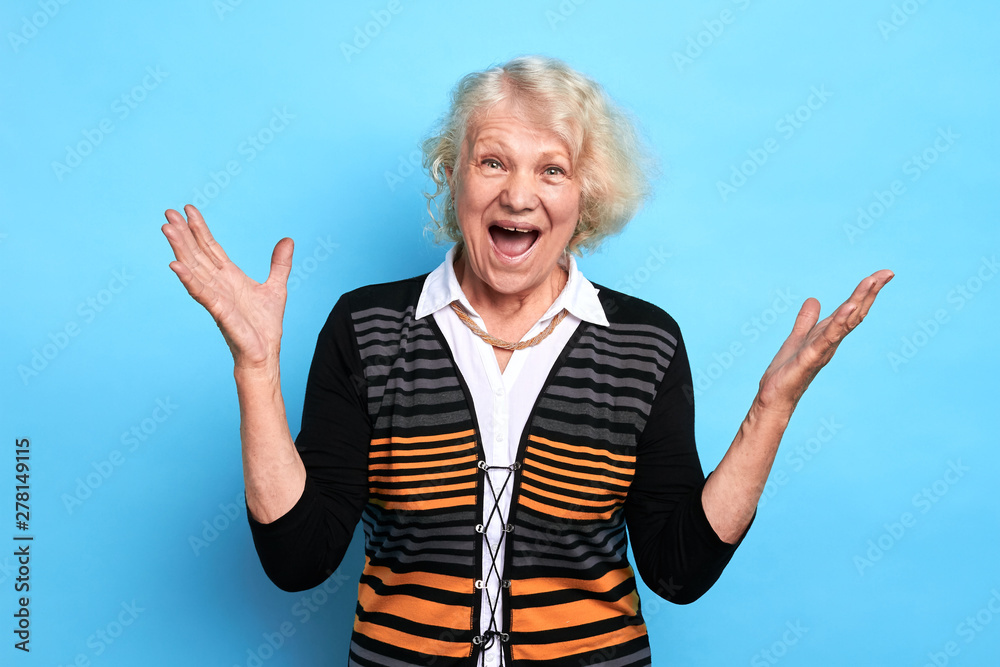 Old excited cheerful lady smiling, laughing, screaming, raising hands ...