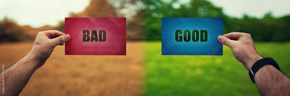 Man hands holding two colored paper sheets with opposite text good and ...