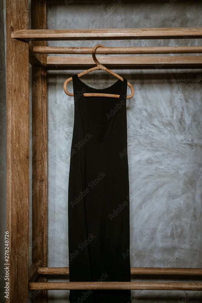 Boho chic Little black dress hanging on a clothing rack, rappan wooden ...